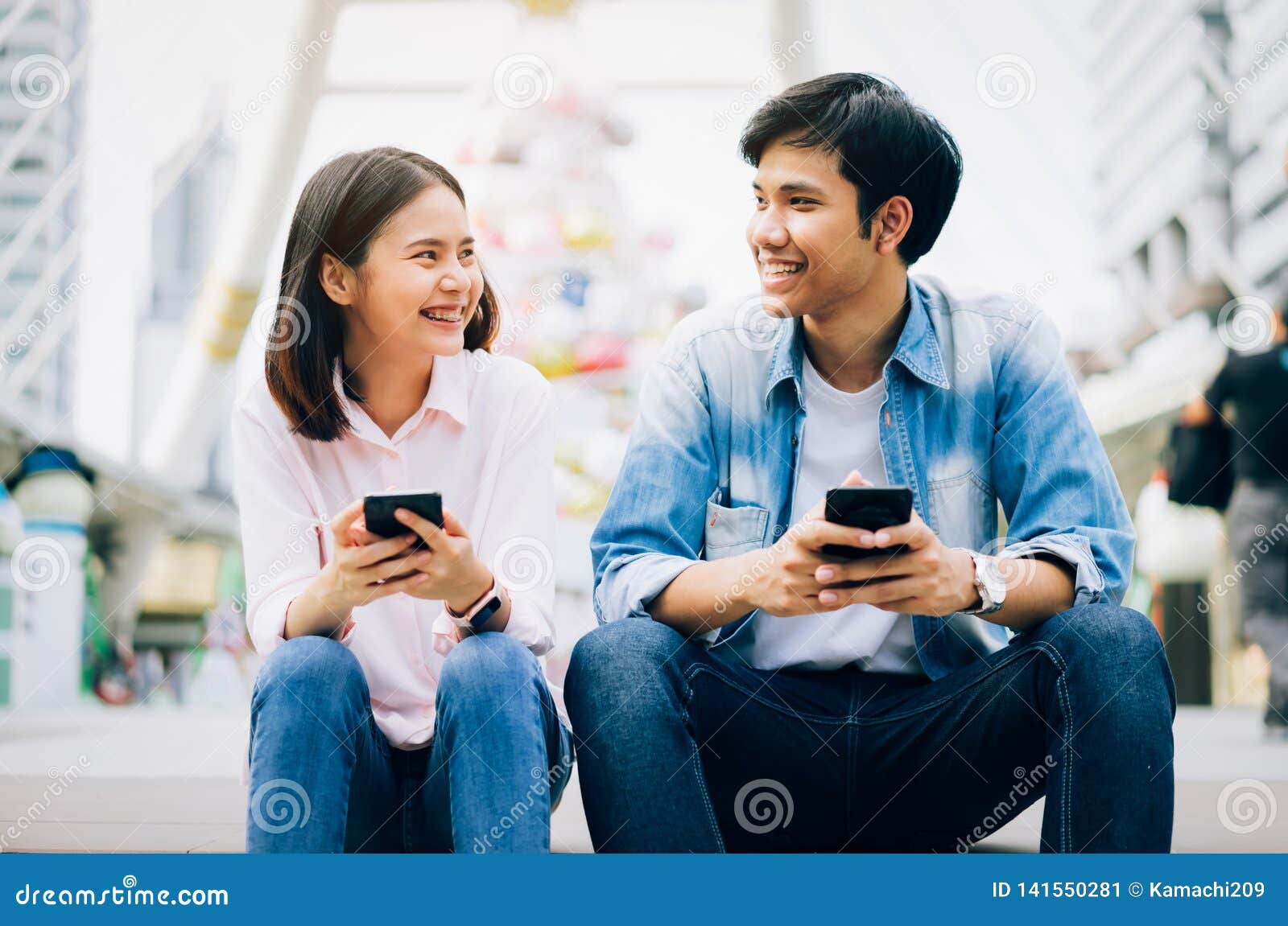 Young People are Using Smartphone and Smiling while Sitting on Free ...