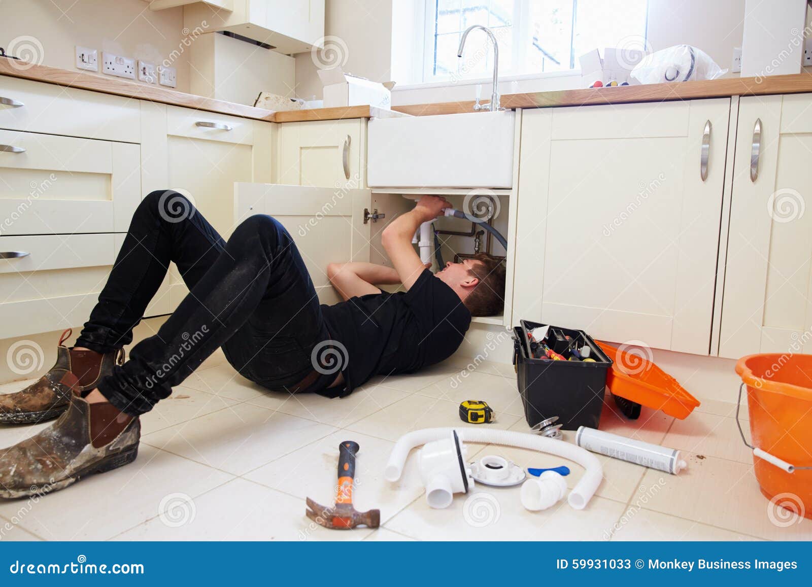Young Plumber at Work Under Kitchen Sink, Tools in Foreground Stock ...