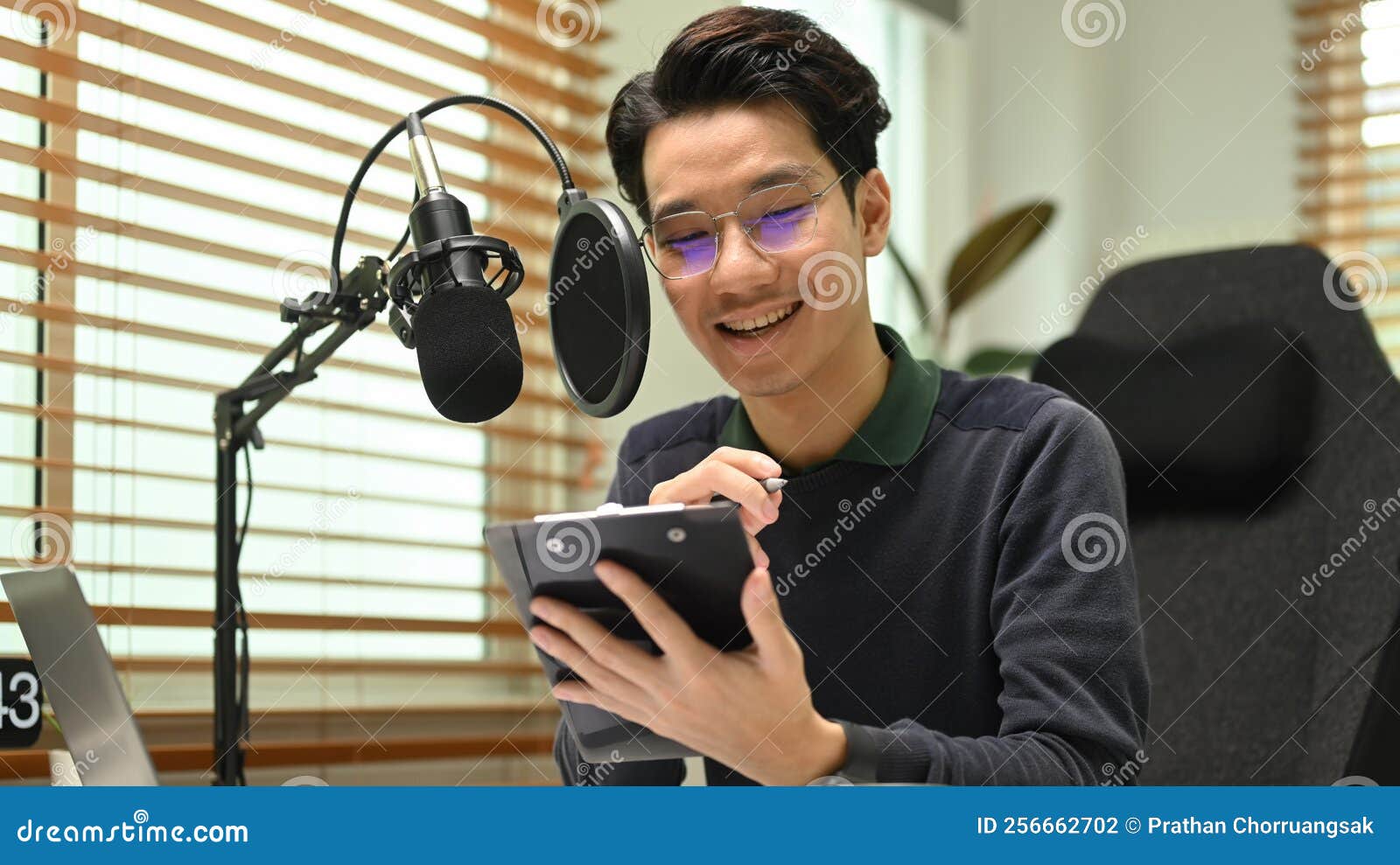 Young Podcaster Using a Microphone and Laptop Computer Recording Audio ...