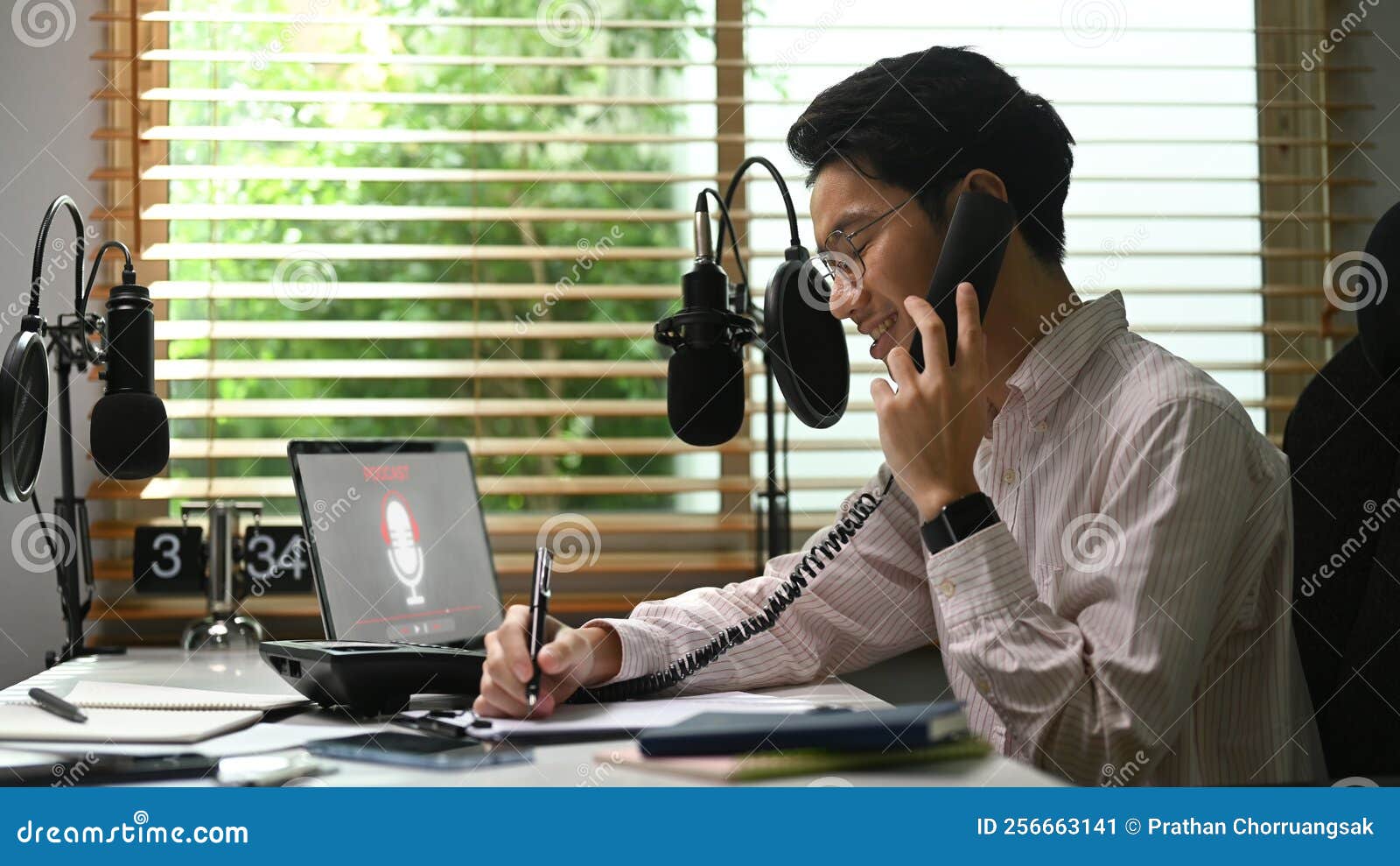 Young Podcaster Using a Microphone and Laptop Computer Recording Audio ...
