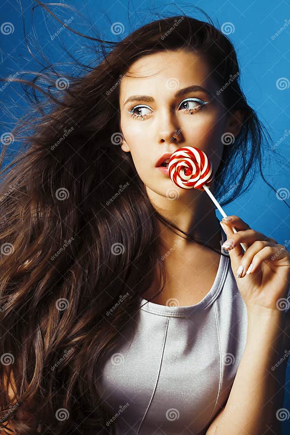 Young Pretty Adorable Brunette Woman With Candy Close Up Posing On Blue
