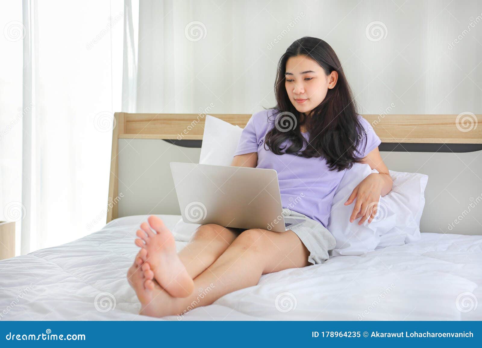 Young Pretty Girl Working from Home on Her Bed Using Computer Laptop To ...