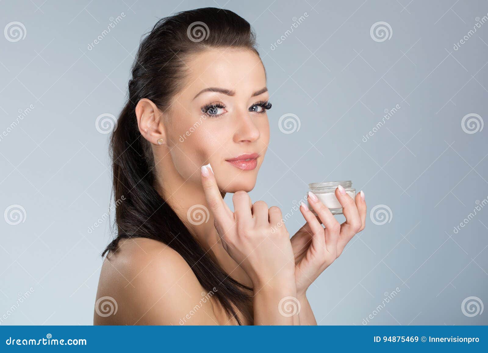 Young Pretty Woman Applying Moisturizing Cream On Face Stock Image
