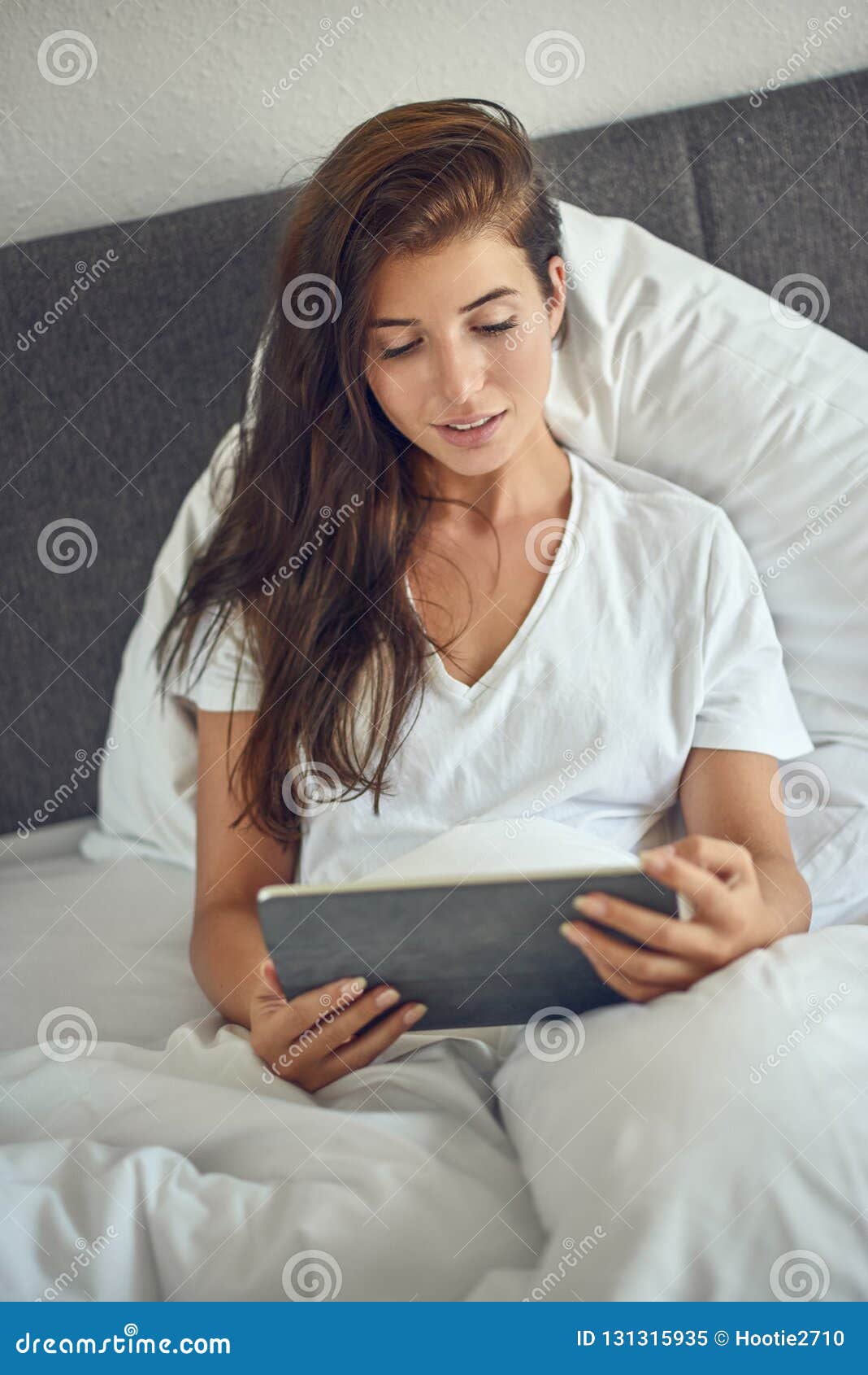 Young Pretty Woman With Long Brunette Hair Lying In Bed Stock Image
