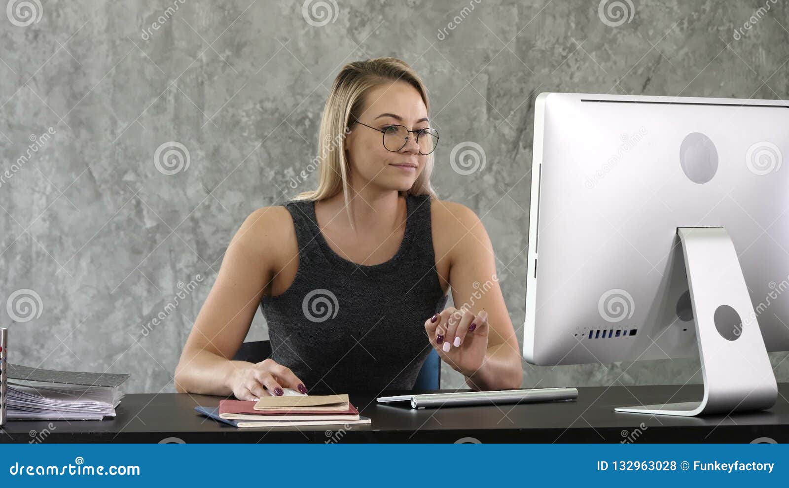 Young Professional Woman Sitting Down at the Desk and Working with ...