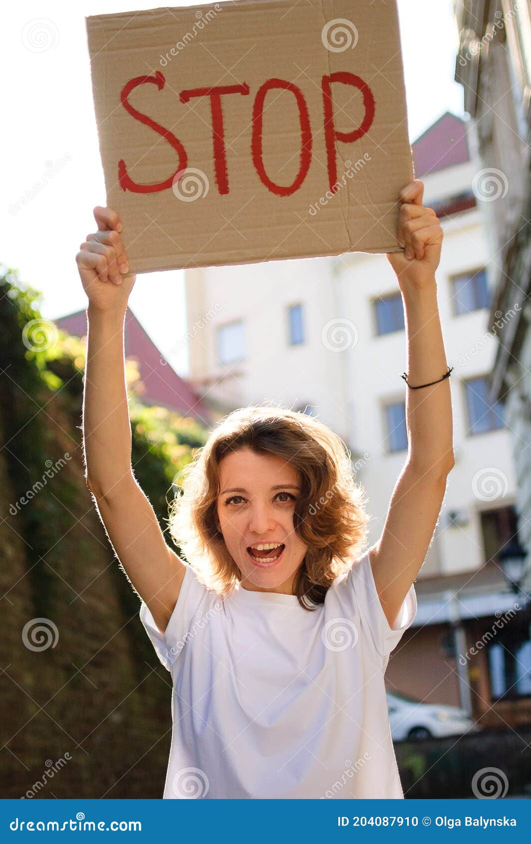 Young Protesting Woman In White Shirt And Jeans Holds Protest Sign