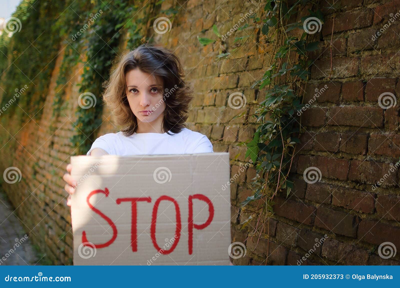 Young Protesting Woman In White Shirt And Jeans Holds Protest Sign