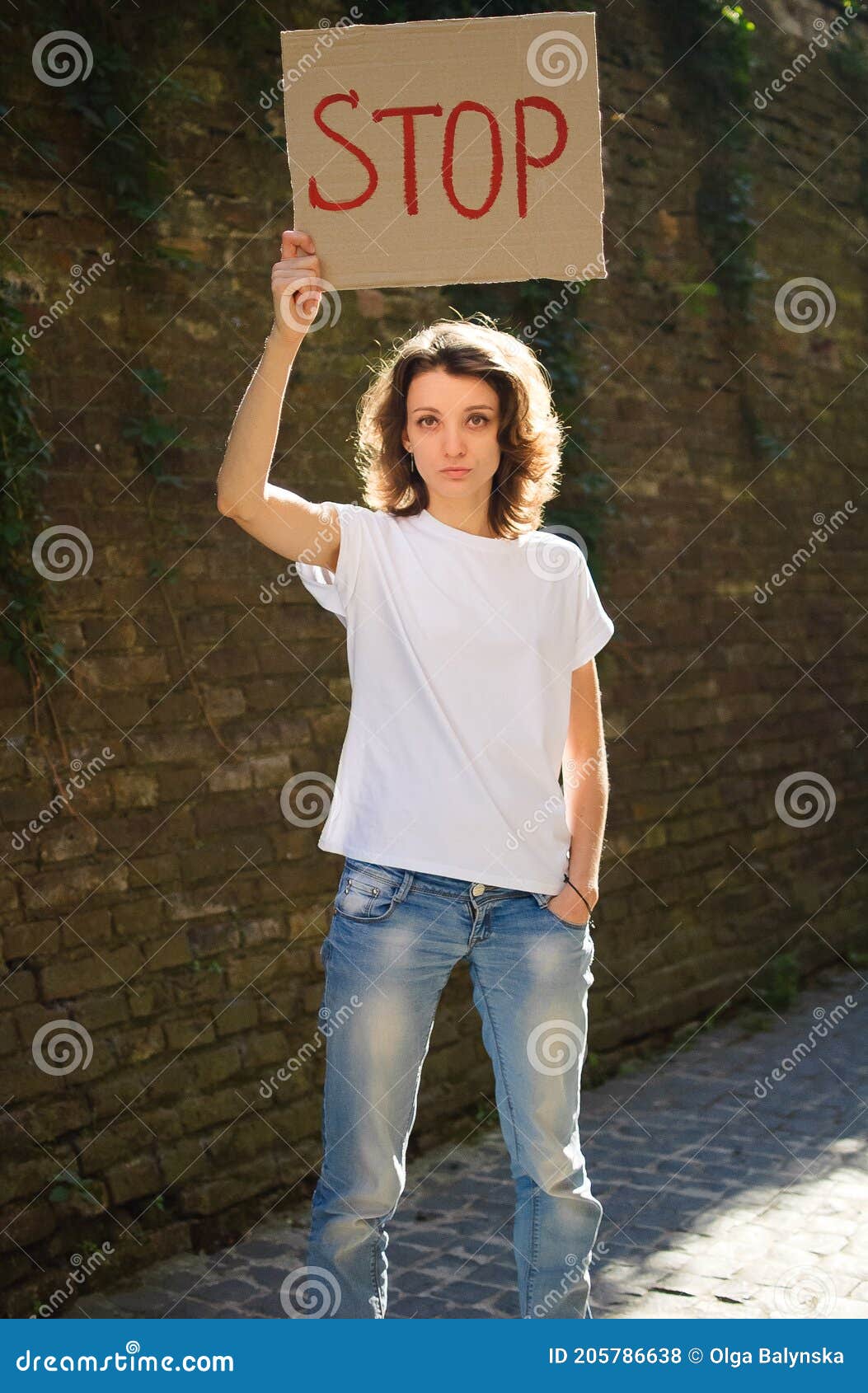 Young Protesting Woman In White Shirt And Jeans Holds Protest Sign