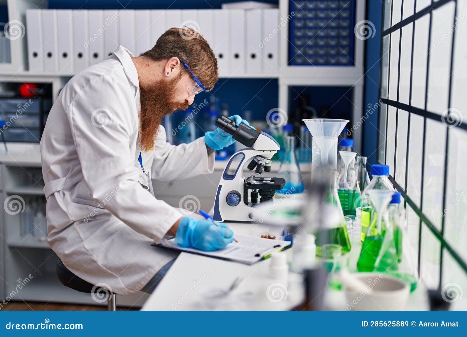 Young Redhead Man Scientist Using Microscope Writing Report Working at ...