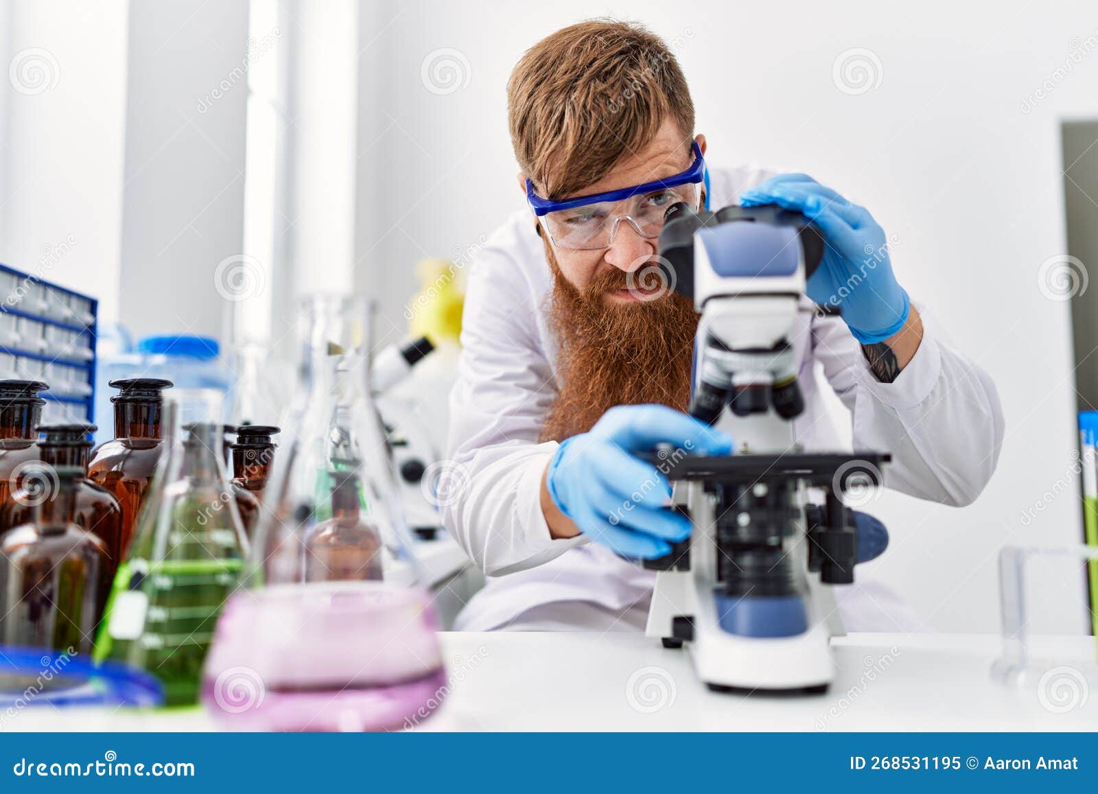 Young Redhead Man Wearing Scientist Uniform Using Microscope at ...