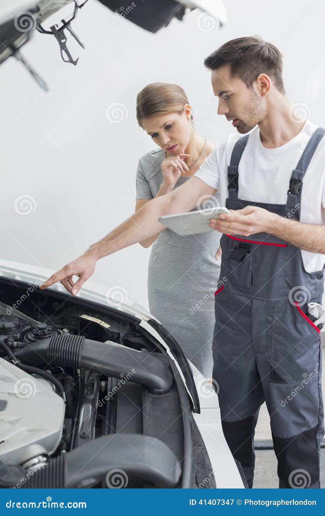 Young Repair Worker Explaining Car Engine To Worried Customer in ...