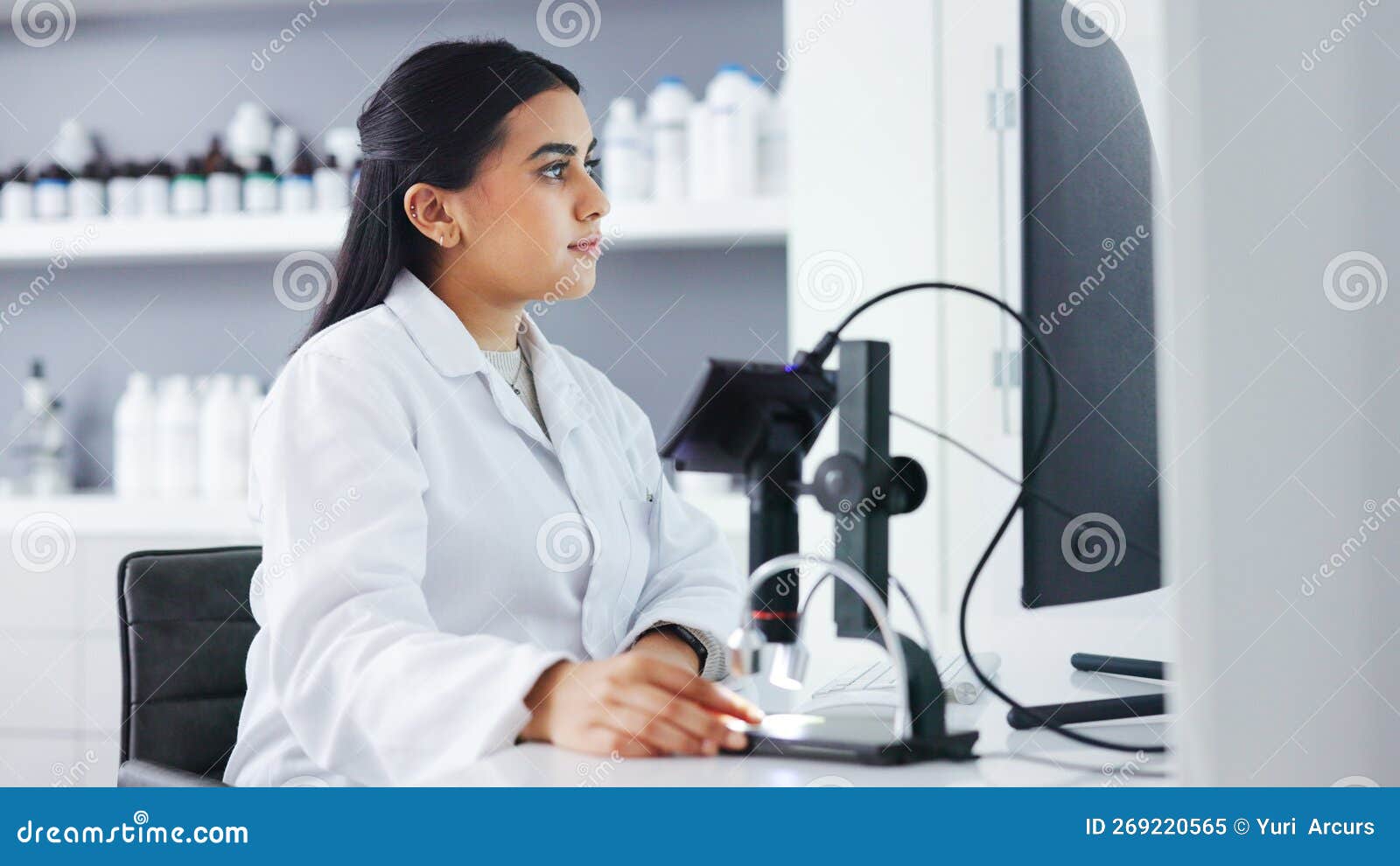Young Scientist Using a Computer and Microscope in a Lab. Female ...