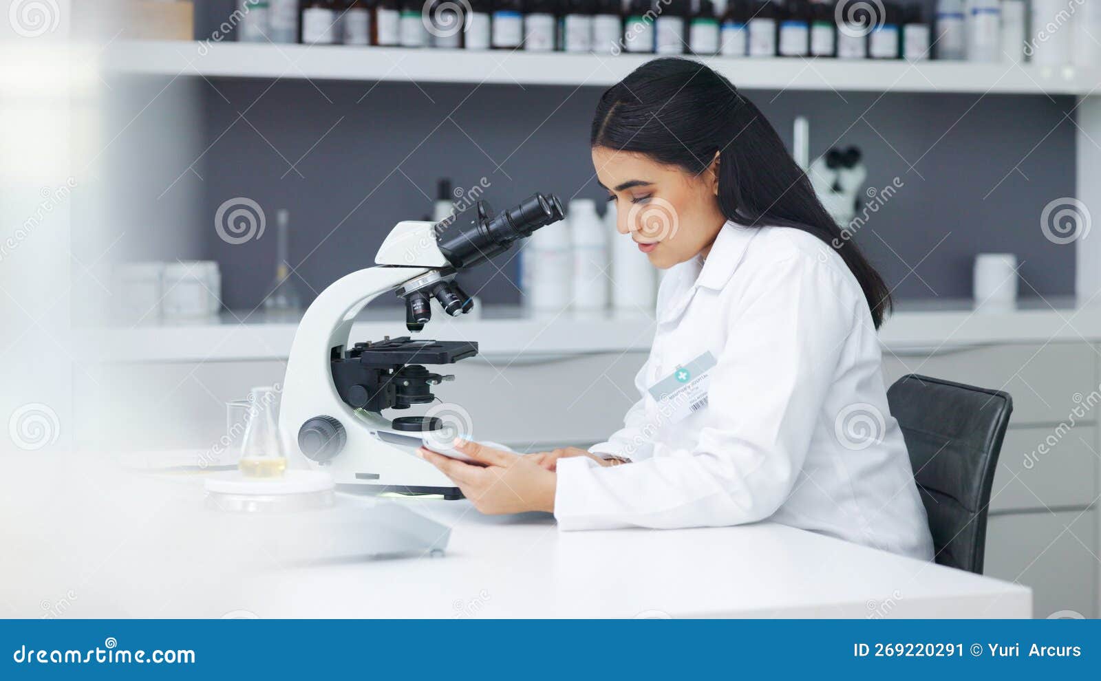 Young Scientist Using a Digital Tablet and Microscope in a Lab. Female ...
