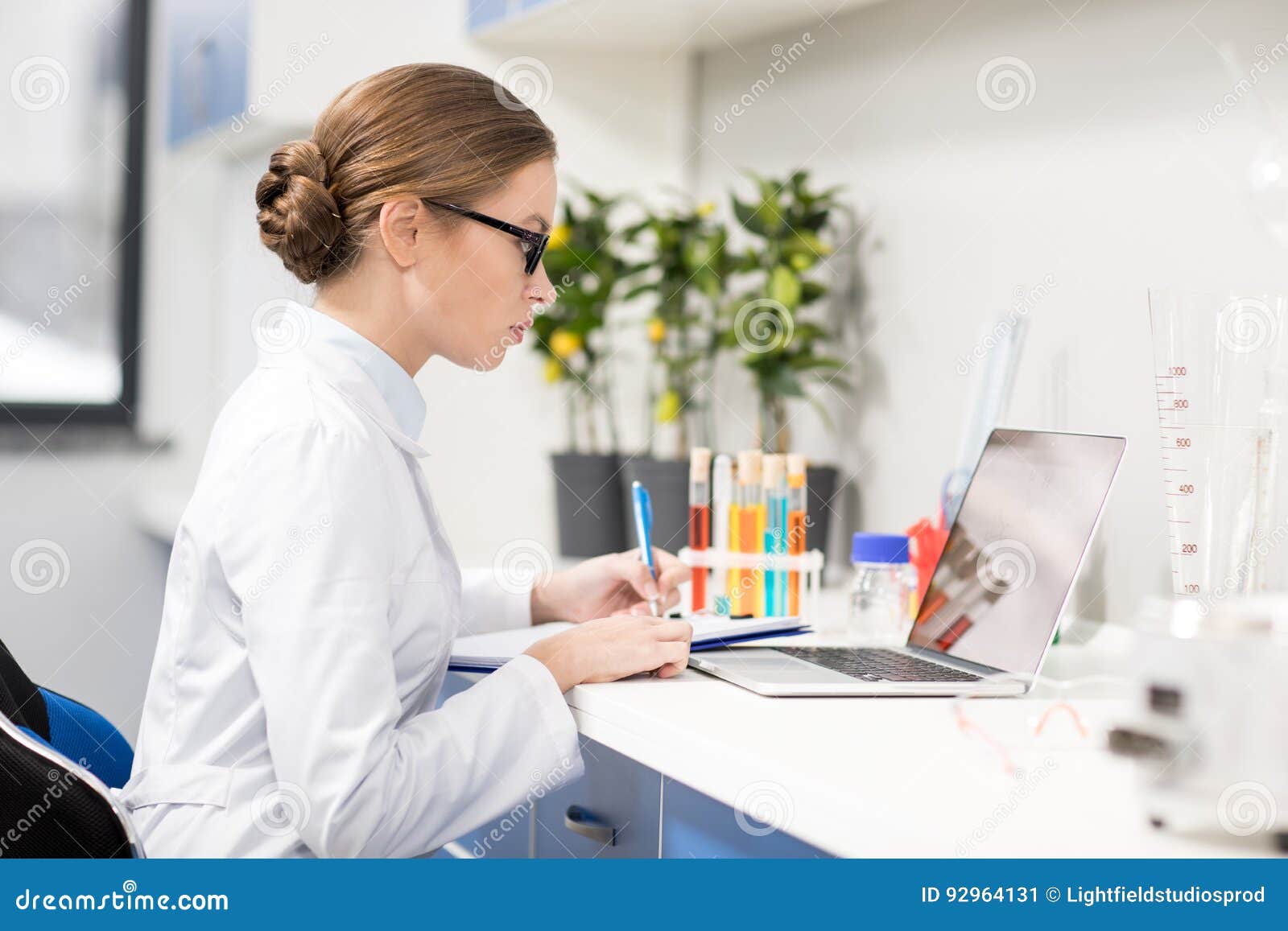 Young Scientist Using Laptop and Writing in Clipboard in Research ...