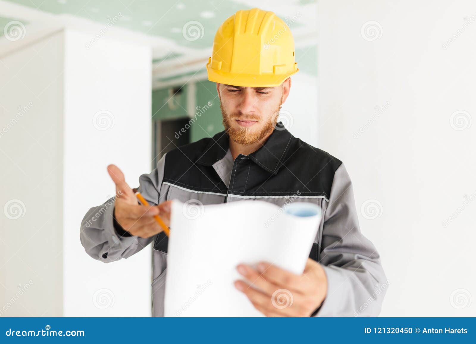 Young Serious Engineer in Work Clothes and Yellow Hardhat Though Stock ...