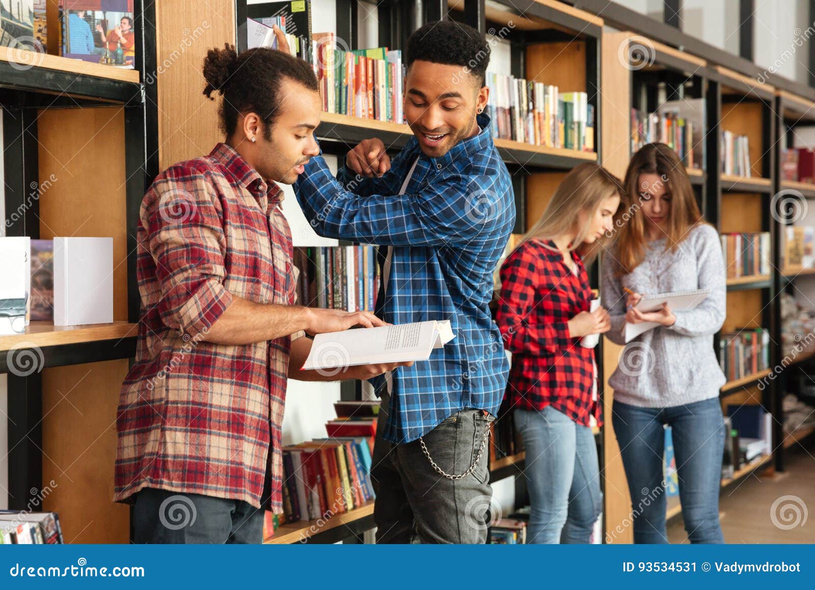 Young Serious Men Students Standing in Library Reading Books Stock ...