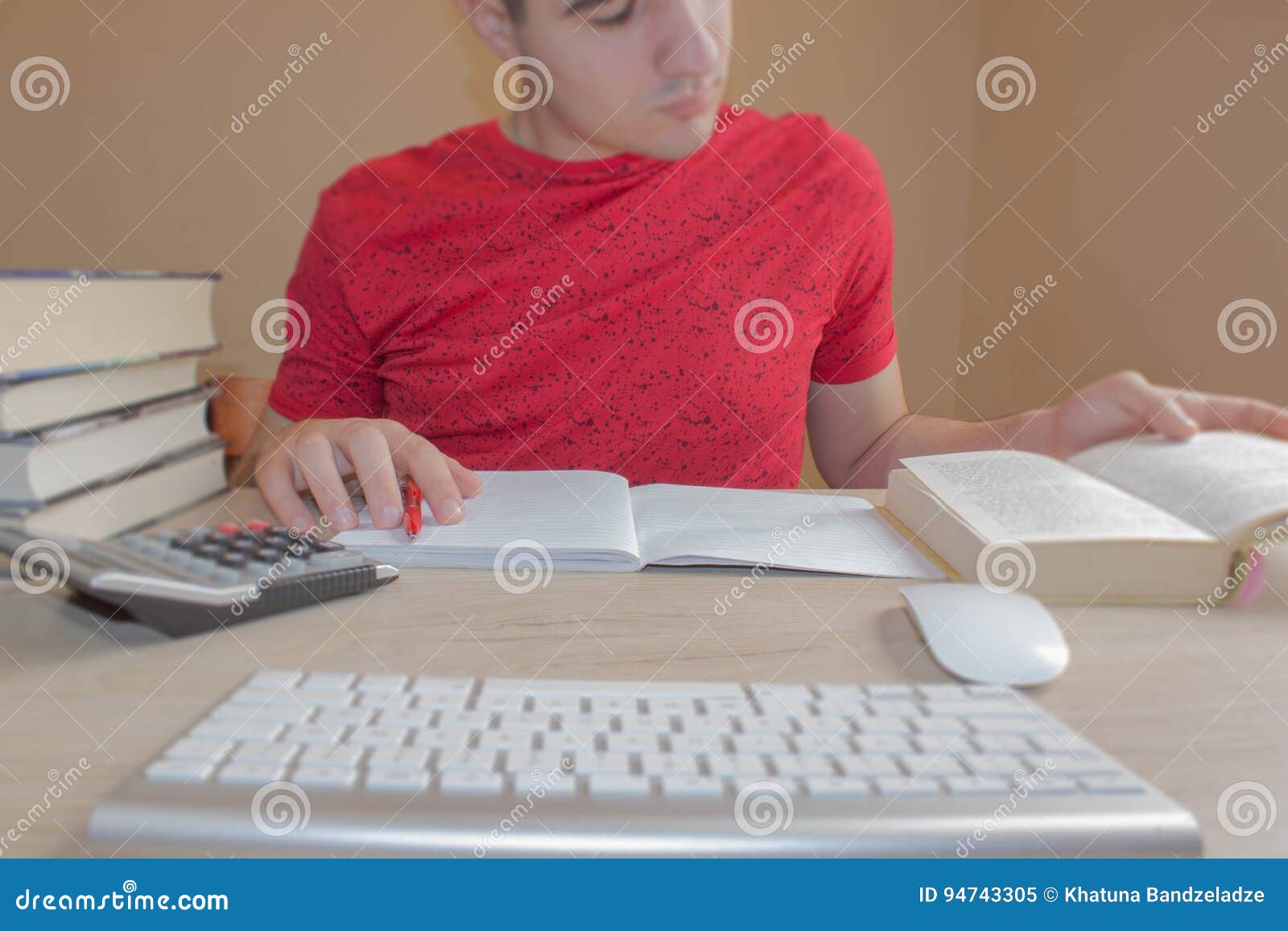 Young Serious Student Reading Book between Books. Man Write in Notebook ...