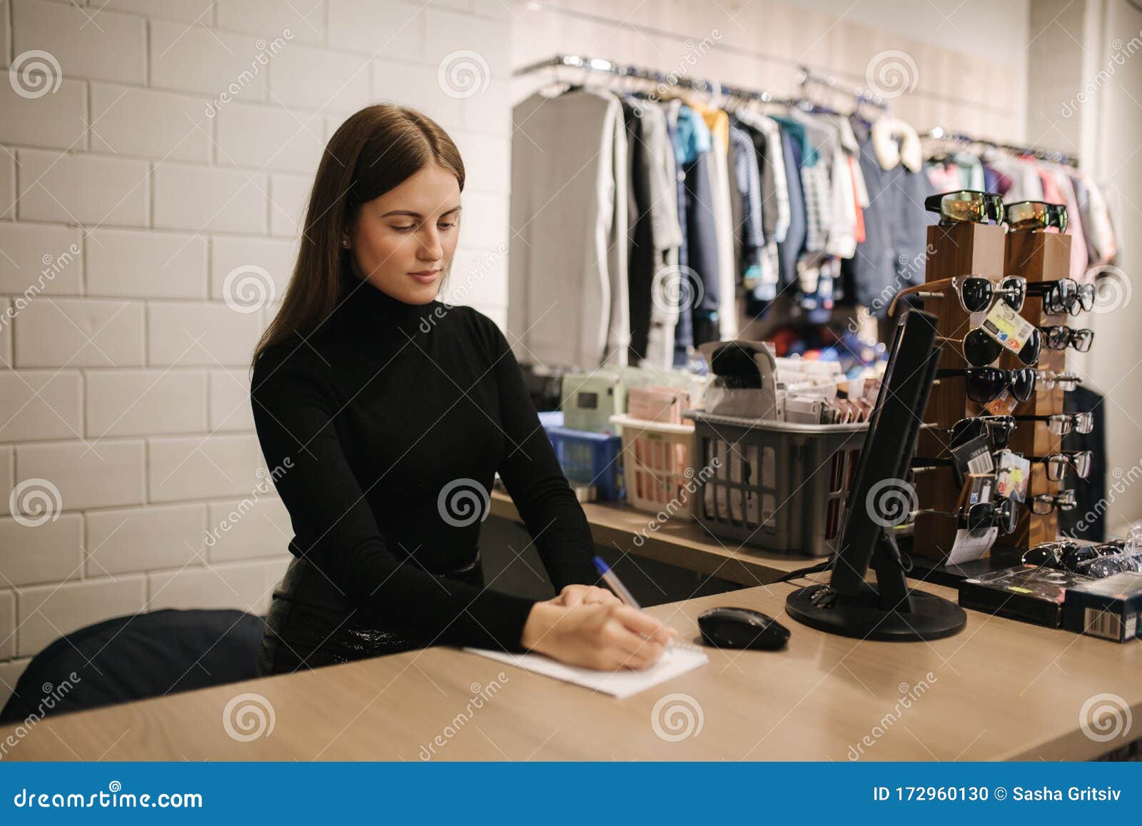 Young Shop Assistant in Clothes Store Working by Comtuper. Beautiful ...
