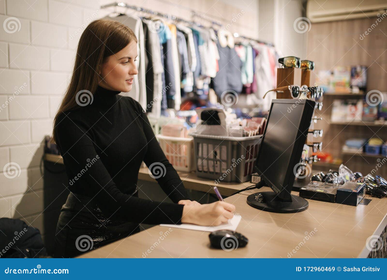 Young Shop Assistant in Clothes Store Working by Comtuper. Beautiful ...