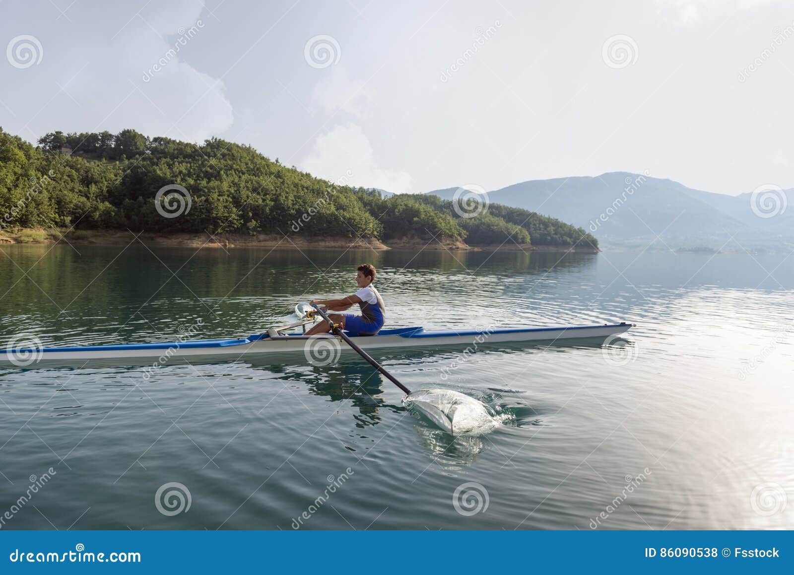 A Young Single Scull Rowing Competitor Paddles on the Tranquil Lake ...