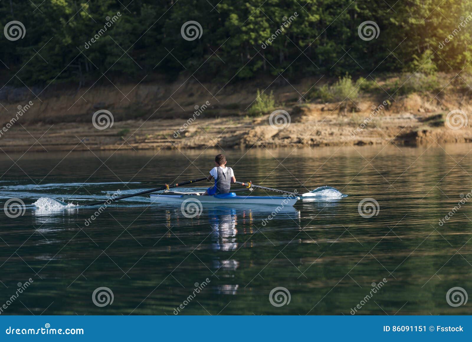 A Young Single Scull Rowing Competitor Paddles on the Tranquil Lake ...