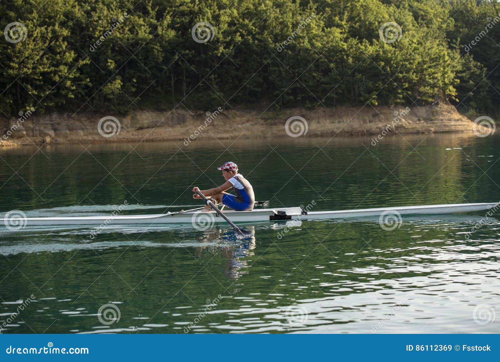 A Young Single Scull Rowing Competitor Paddles on the Tranquil Lake ...