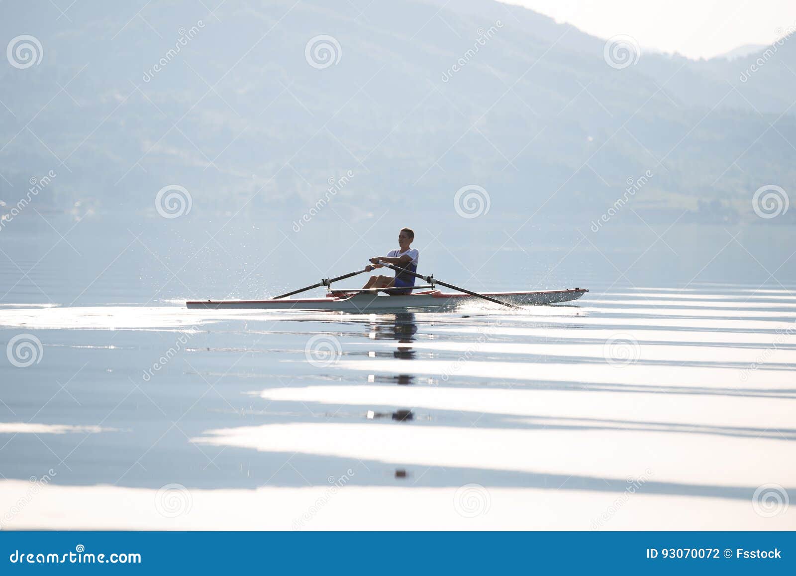 A Young Single Scull Rowing Competitor Paddles on the Tranquil Lake ...