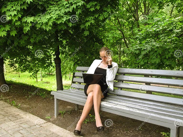 Young Slim Woman Talking On The Phone And Looking Into The Laptop While