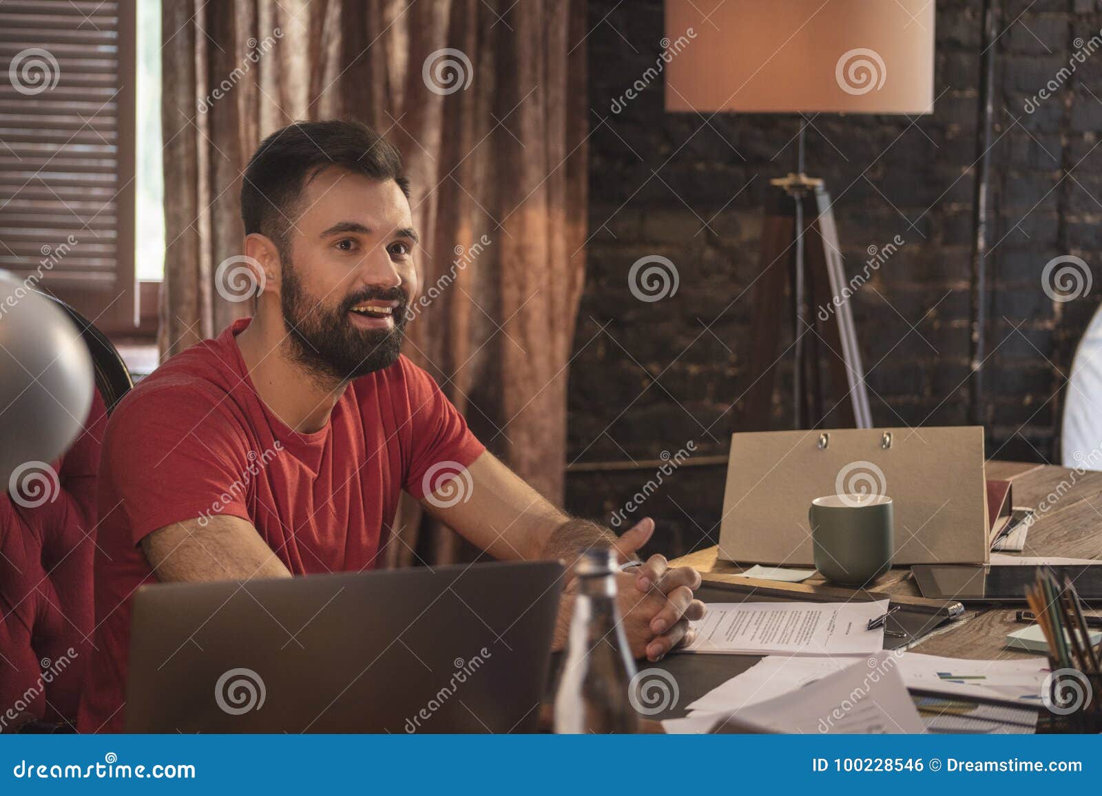 Young Smiling Business Man with Beard Sitting in Start Up Dark Office ... Young Smiling Business Man with Beard Sitting in Start Up Dark Office ...