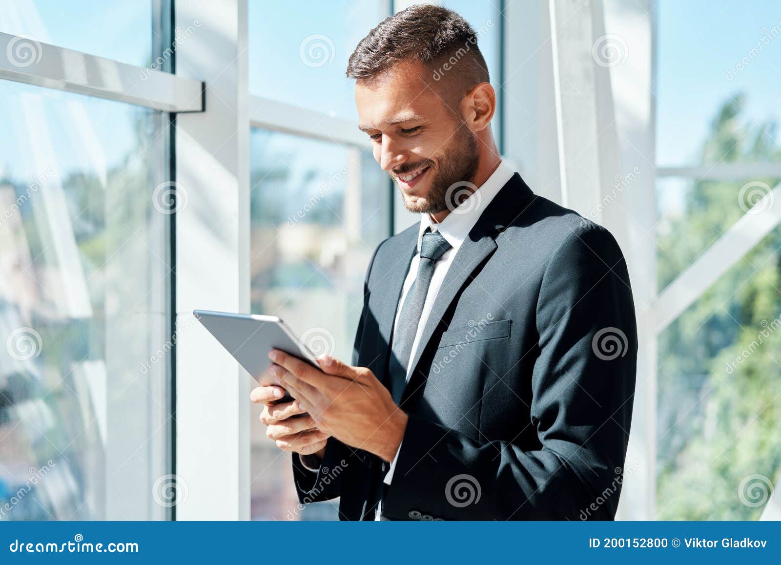 Young Smiling Businessman Working On Tablet In Modern Creative Office