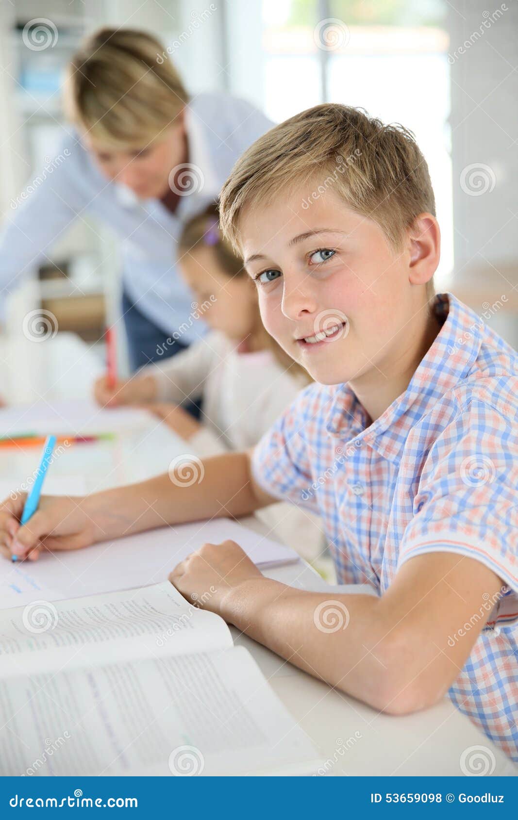 Young Smiling Schoolboy Doing Excercises in Notebook Stock Photo ...
