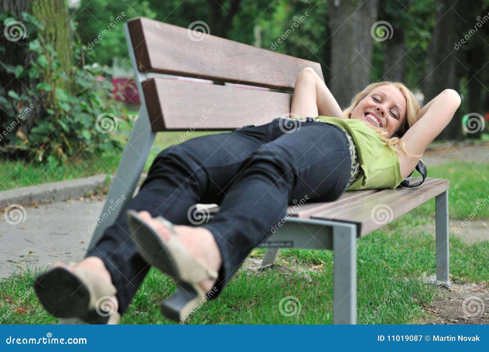 Young Smiling Woman Lying on Bench Outdoors Stock Image - Image of ...
