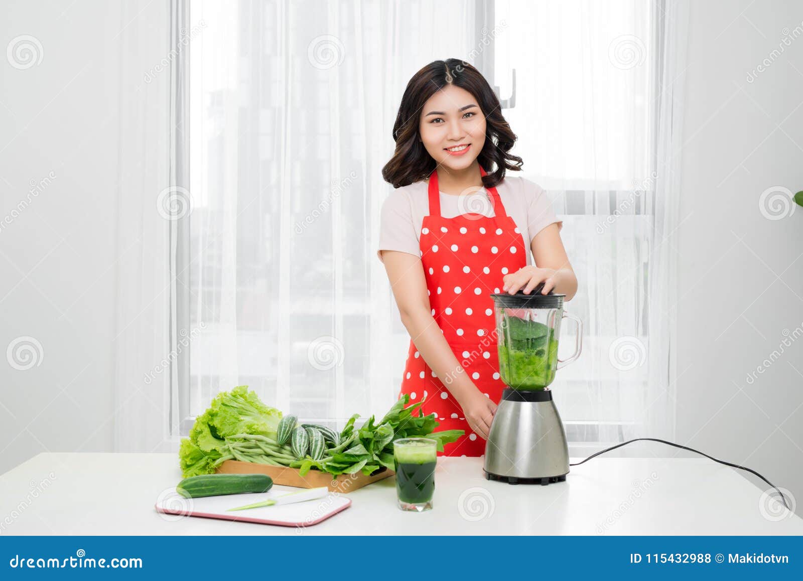 Young Smiling Woman Making Smoothie With Fresh Greens In The Blender In