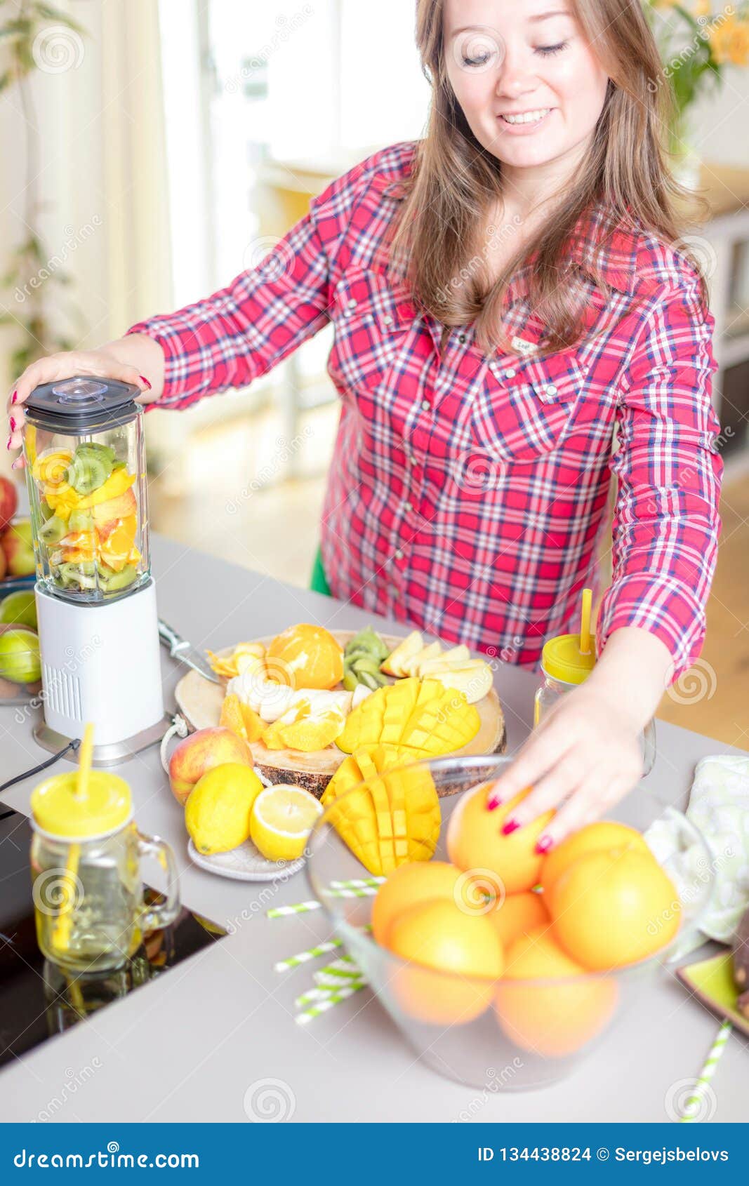 Young Smiling Woman Making Smoothie With Fresh Greens In The Blender In