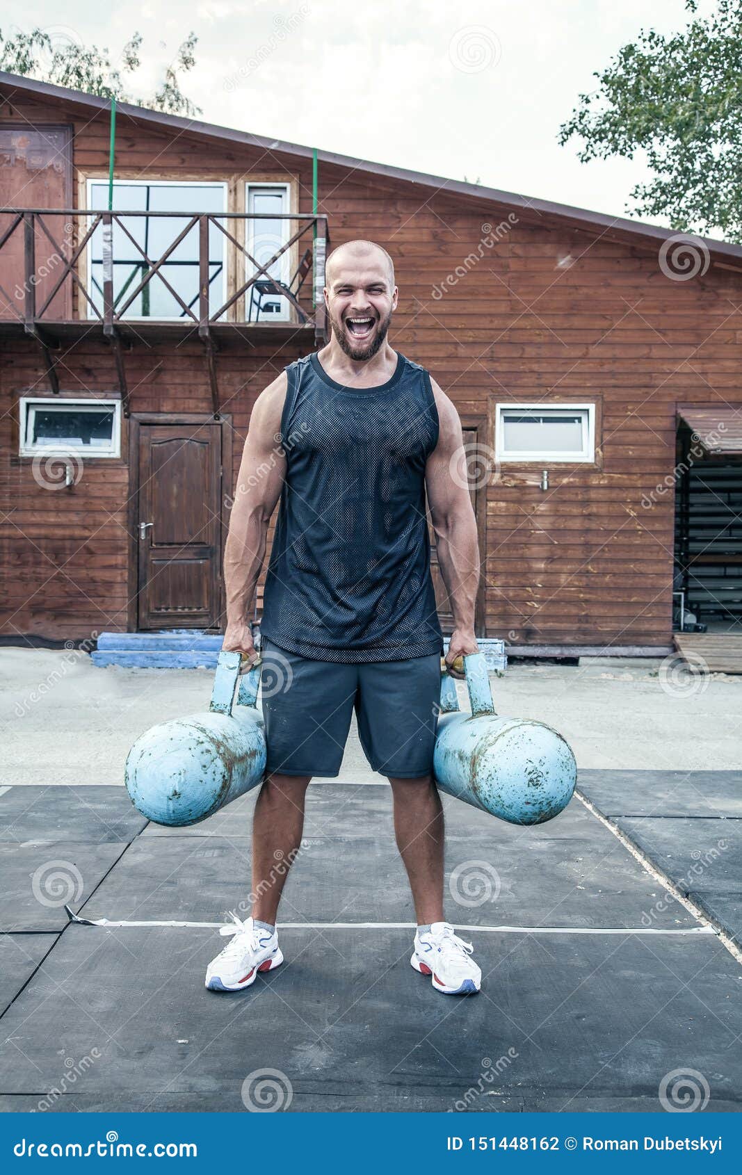 Young Strong Man Bodybuilder with Big Barrels in Hands Screaming To the ...