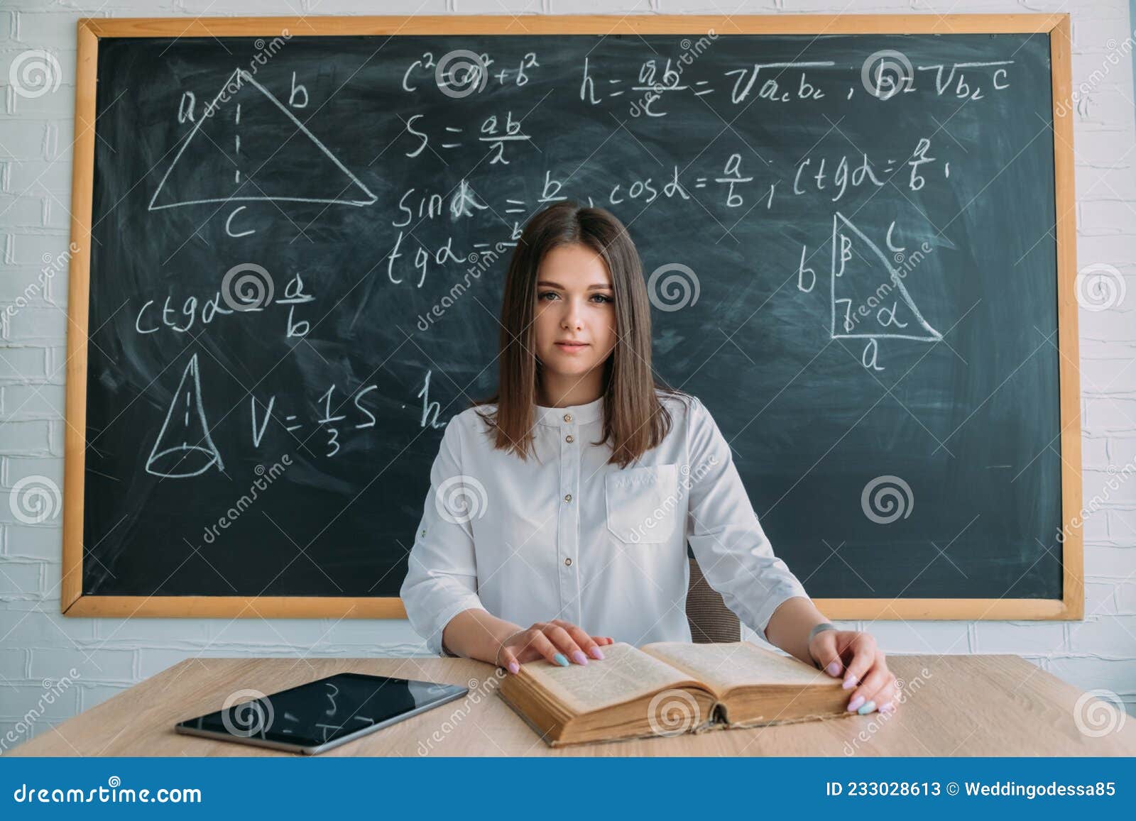 A Young Student Sitting at the Table, Teaches Mathematics Looking at ...