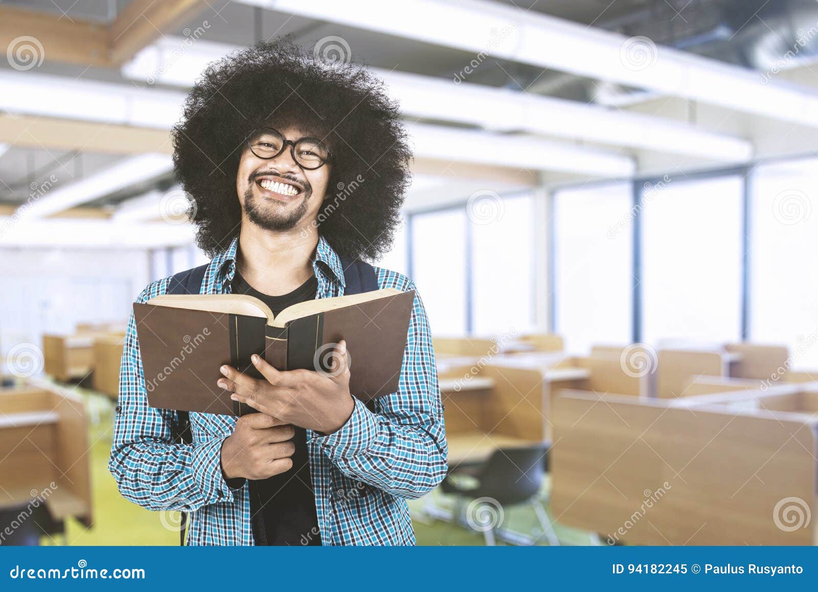 Young Student Smiling with Book in Classroom Stock Image - Image of ...