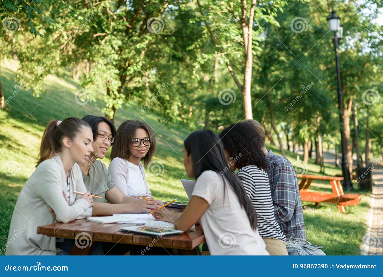 Young Students Sitting and Studying Outdoors while Talking. Stock Photo ...