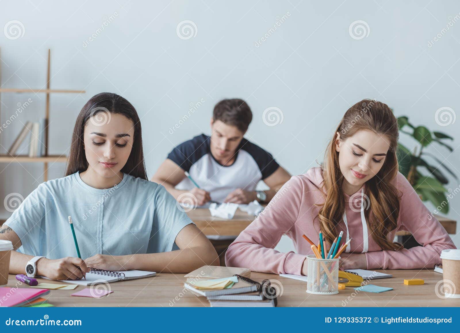 Young Students Sitting at Tables and Writing Stock Photo - Image of ...