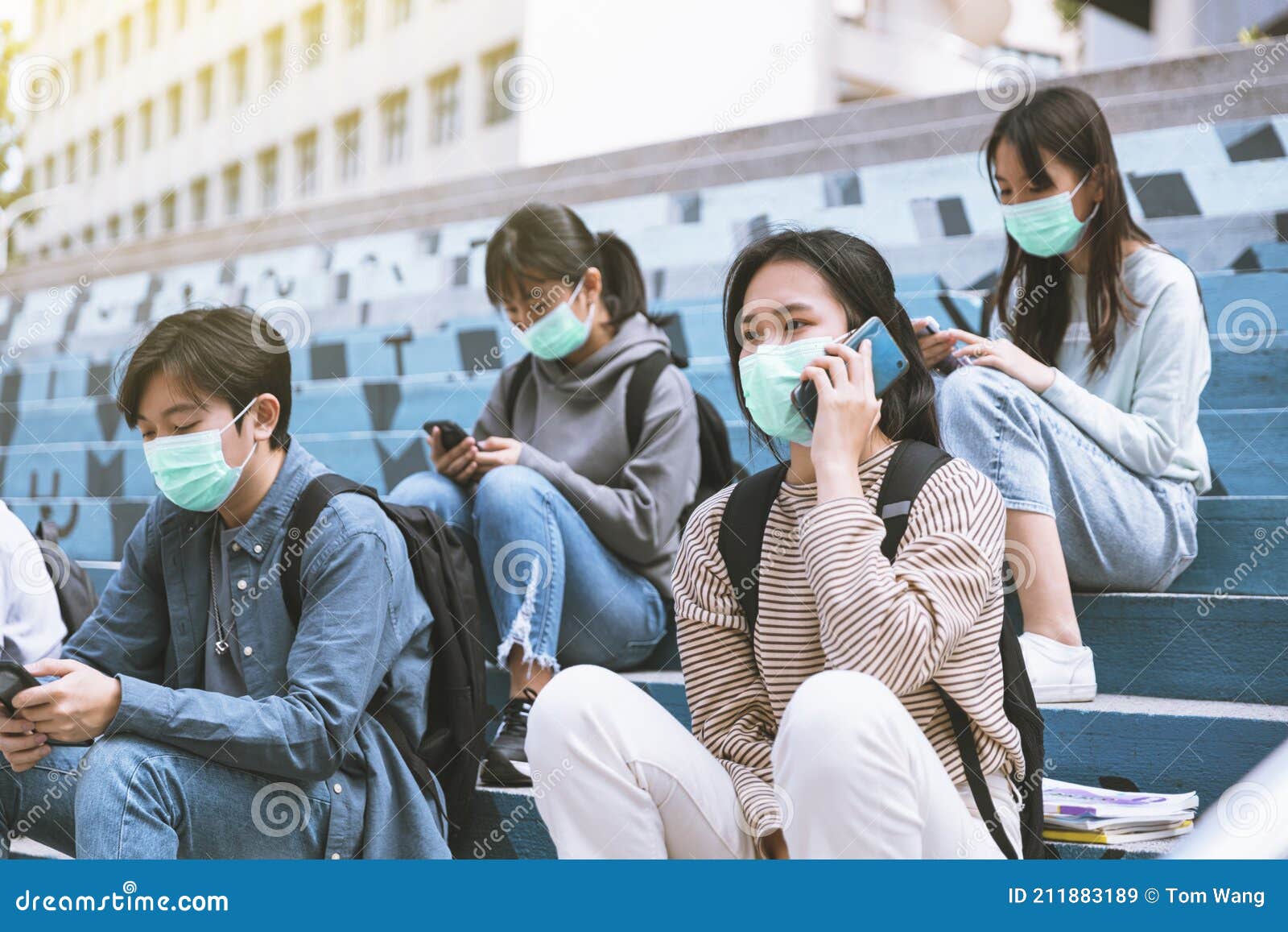 Young Students Wearing with Face Masks and Watching the Mobile Phone on ...