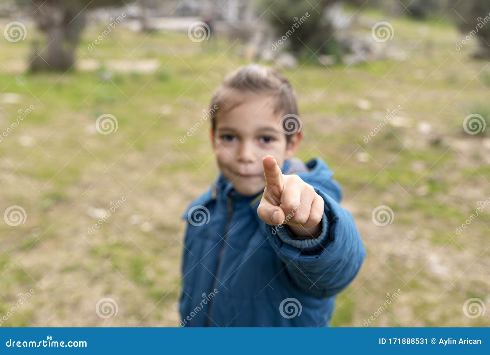 Young Sweet Boy is Pointing with His Finger on the Grass among the ...