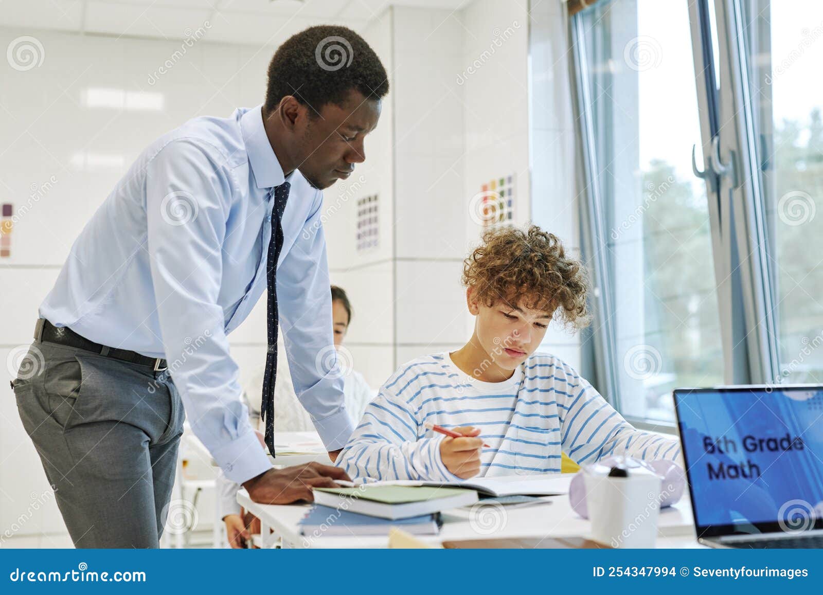 Young Teacher Helping Boy in School Stock Photo - Image of classroom ...