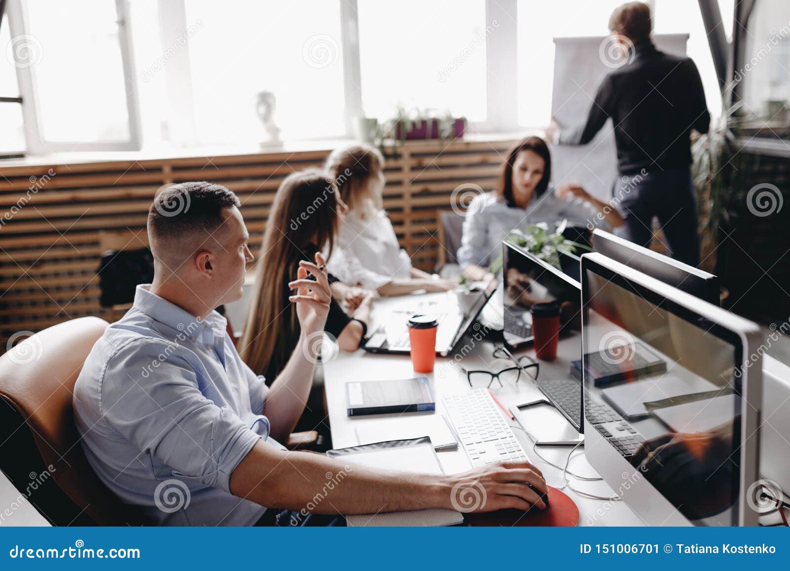 Young Team of the Colleagues Works Sitting at the Desks with a Laptop ...