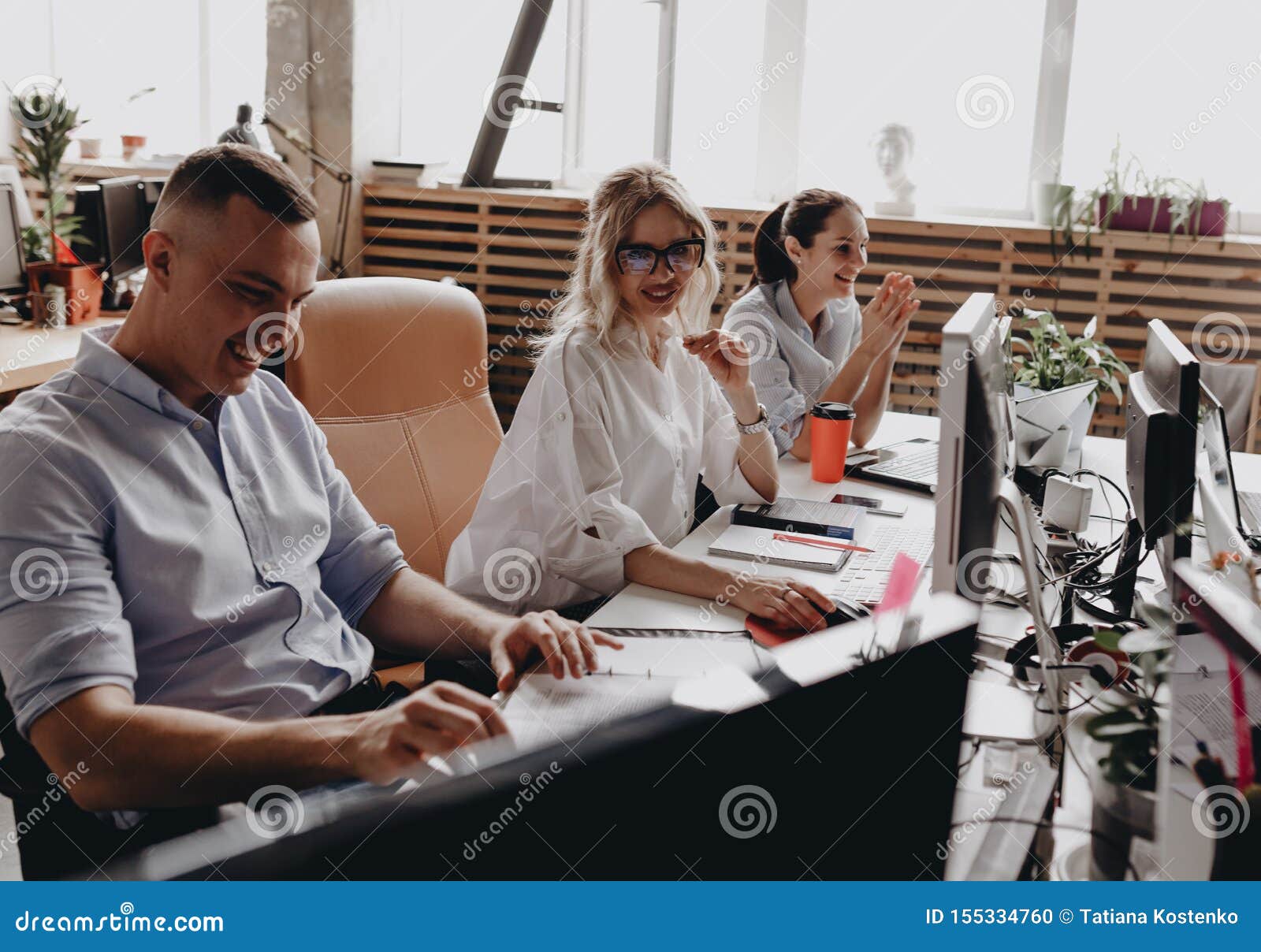 Young Team of the Colleagues Works Sitting at the Desks with a Laptop ...