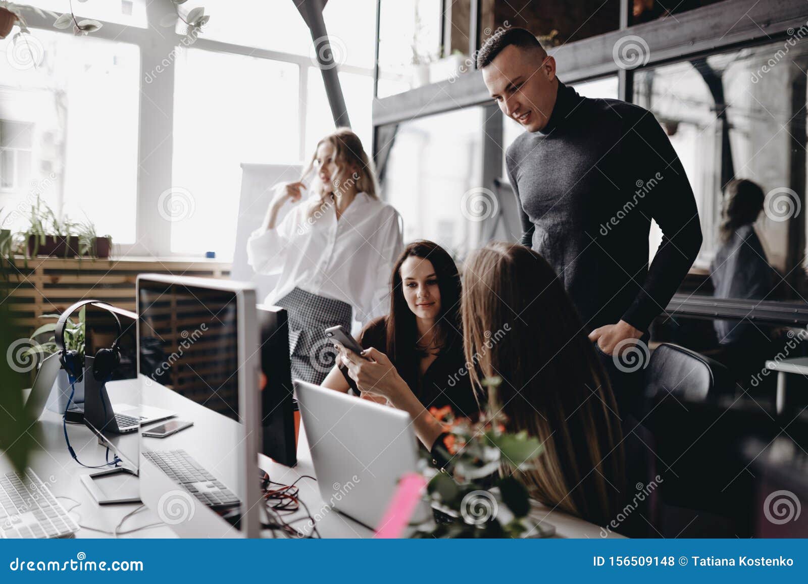Young Team Works at a Desks with a Computer and Laptops in a Light ...