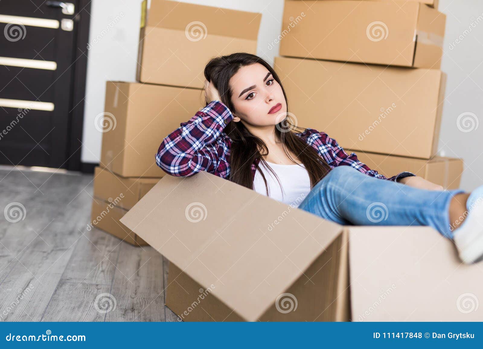 Young Tired Woman Sitting Inside a Box among a Stack of Moving Boxes ...