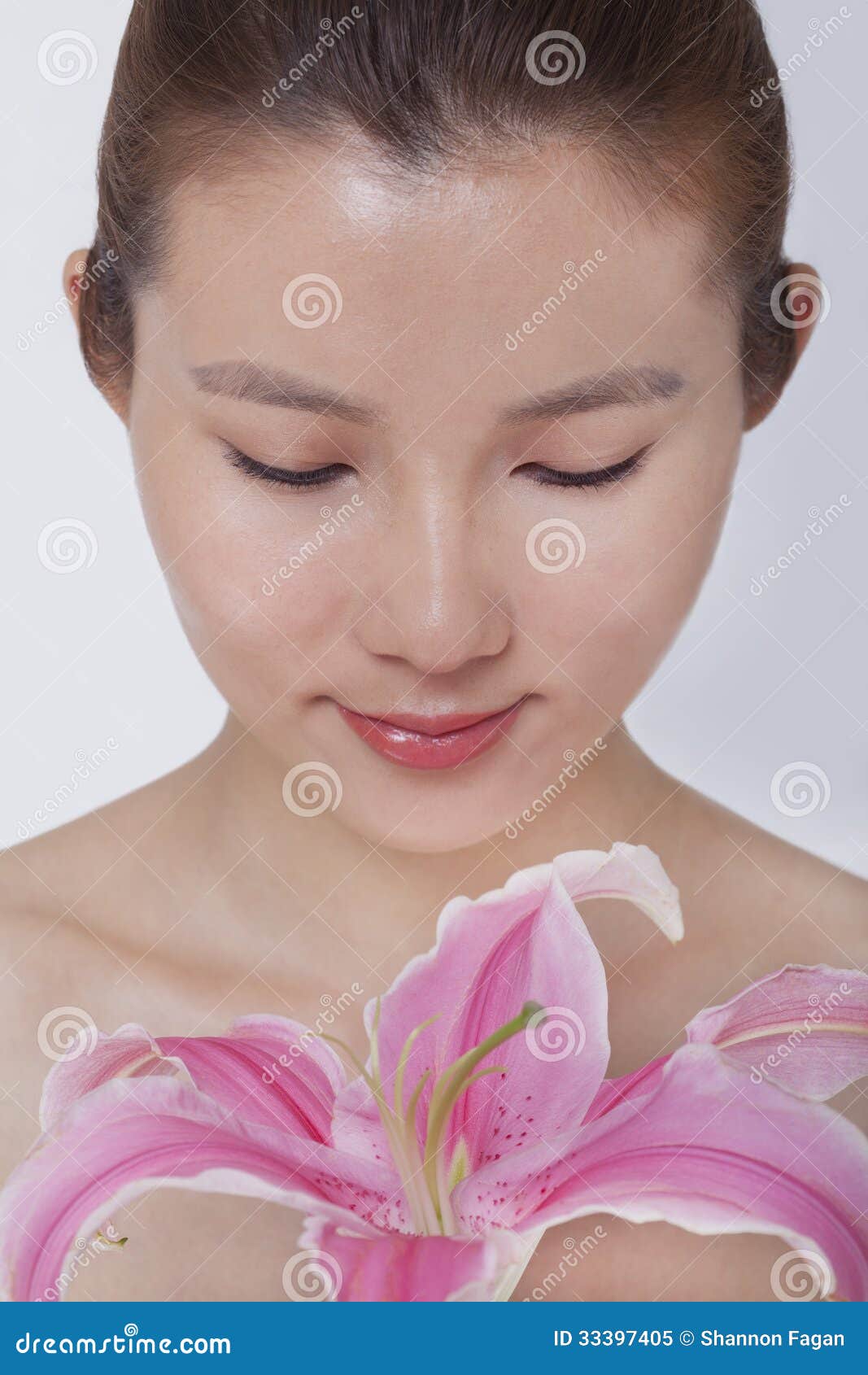 Young Tranquil Woman Looking Down at a Large Pink Flower, Studio Shot ...