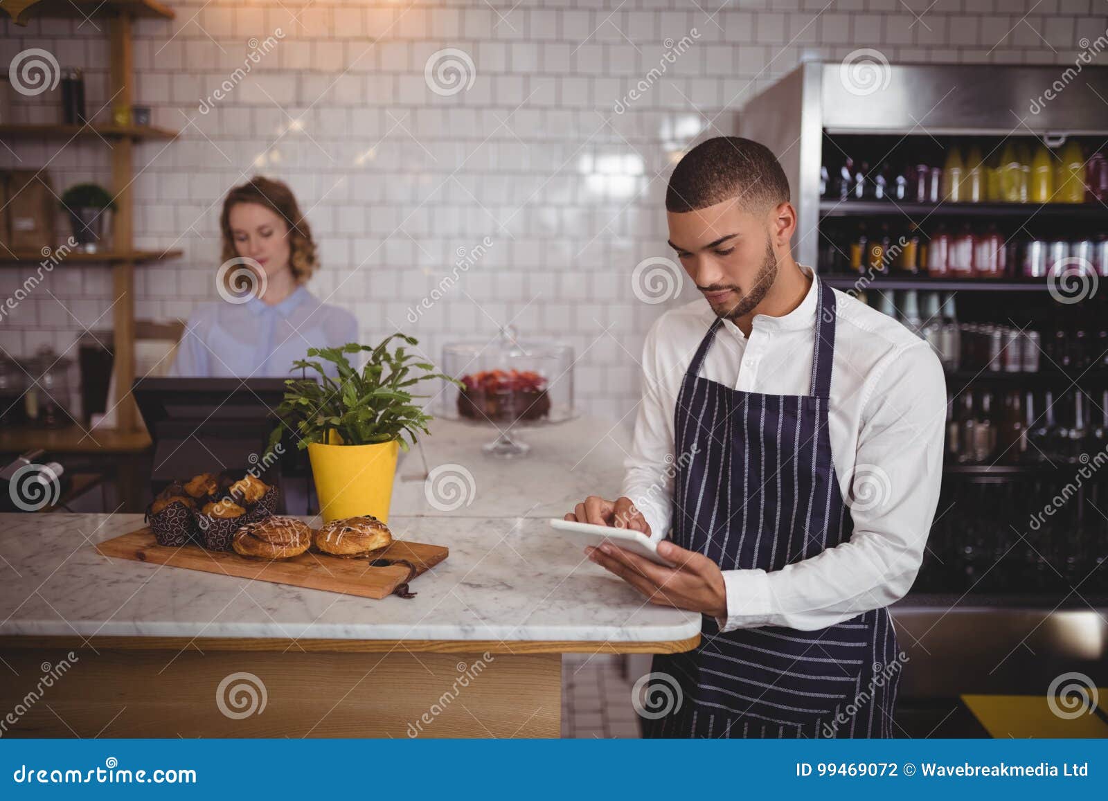 Young Waiter Using Digital Tablet while Standing by Counter Stock Photo ...