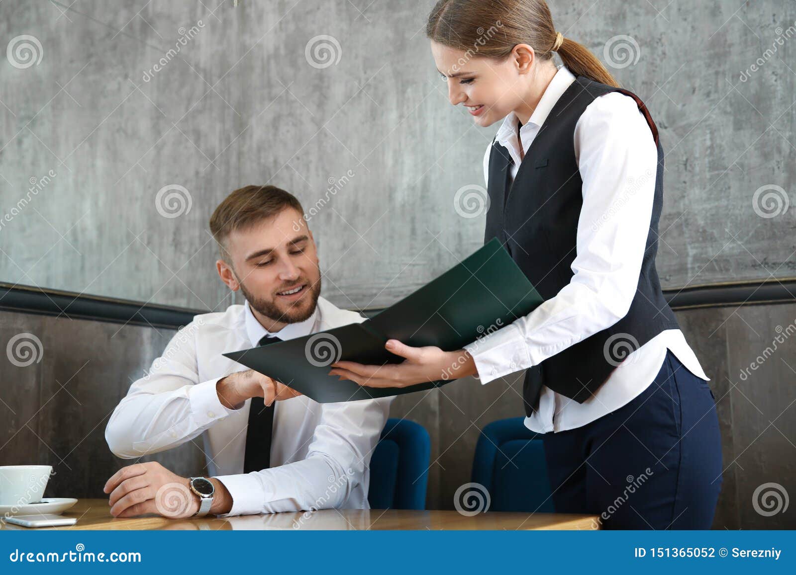 Young Waitress Showing Man a Menu in Restaurant Stock Photo - Image of ...