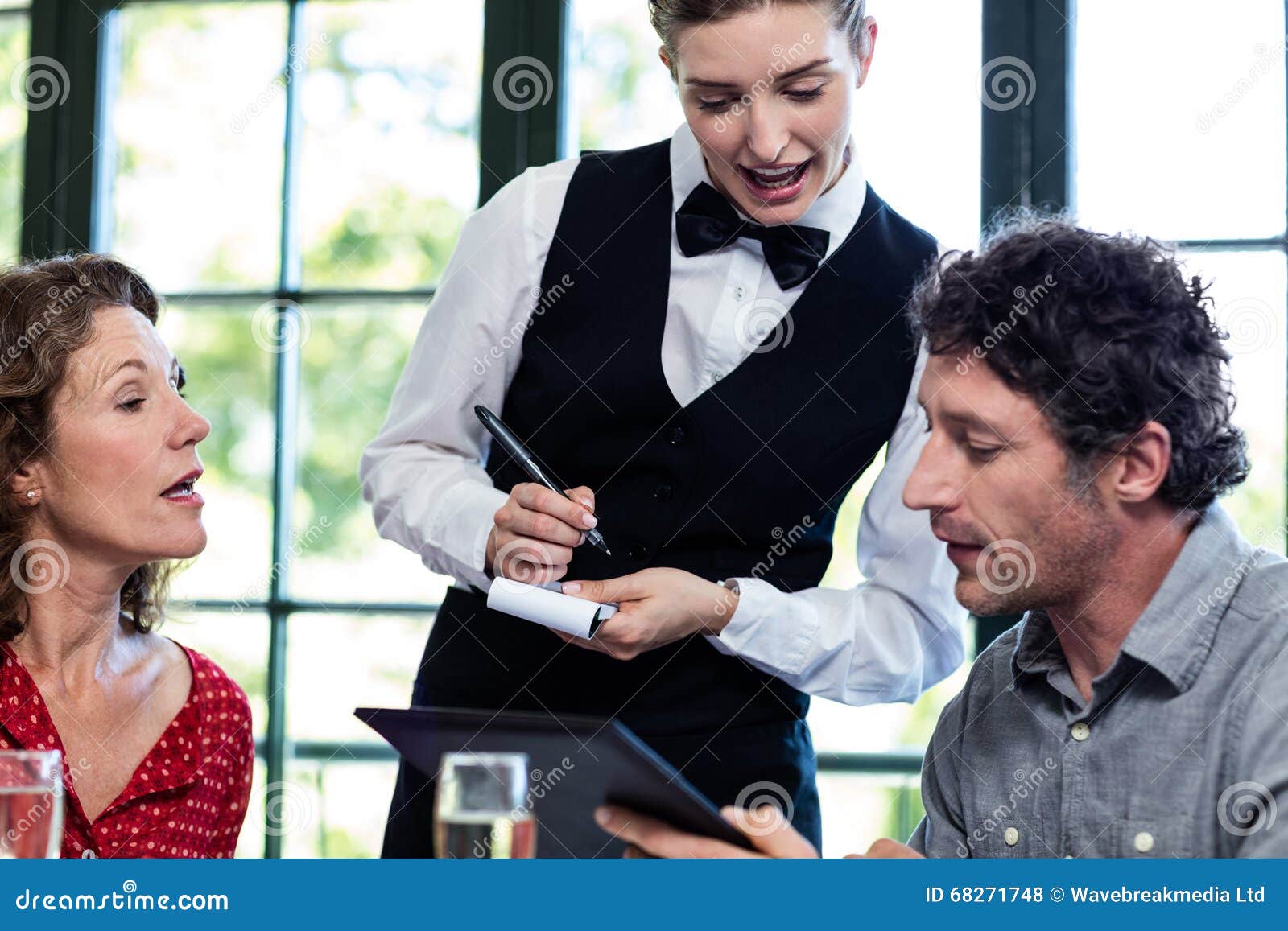 Young Waitress Taking an Order from a Couple Stock Photo - Image of ...
